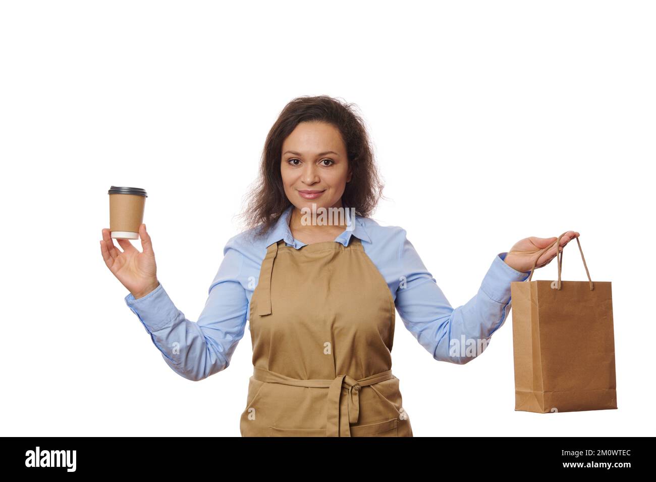 Cute woman waitress in beige chef apron, holds cardboard cup of ...