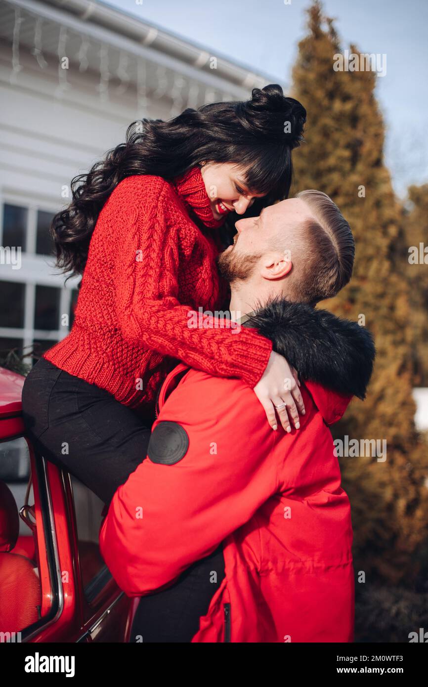 Affectionate boyfriend and his lady cuddling by a red car Stock Photo ...