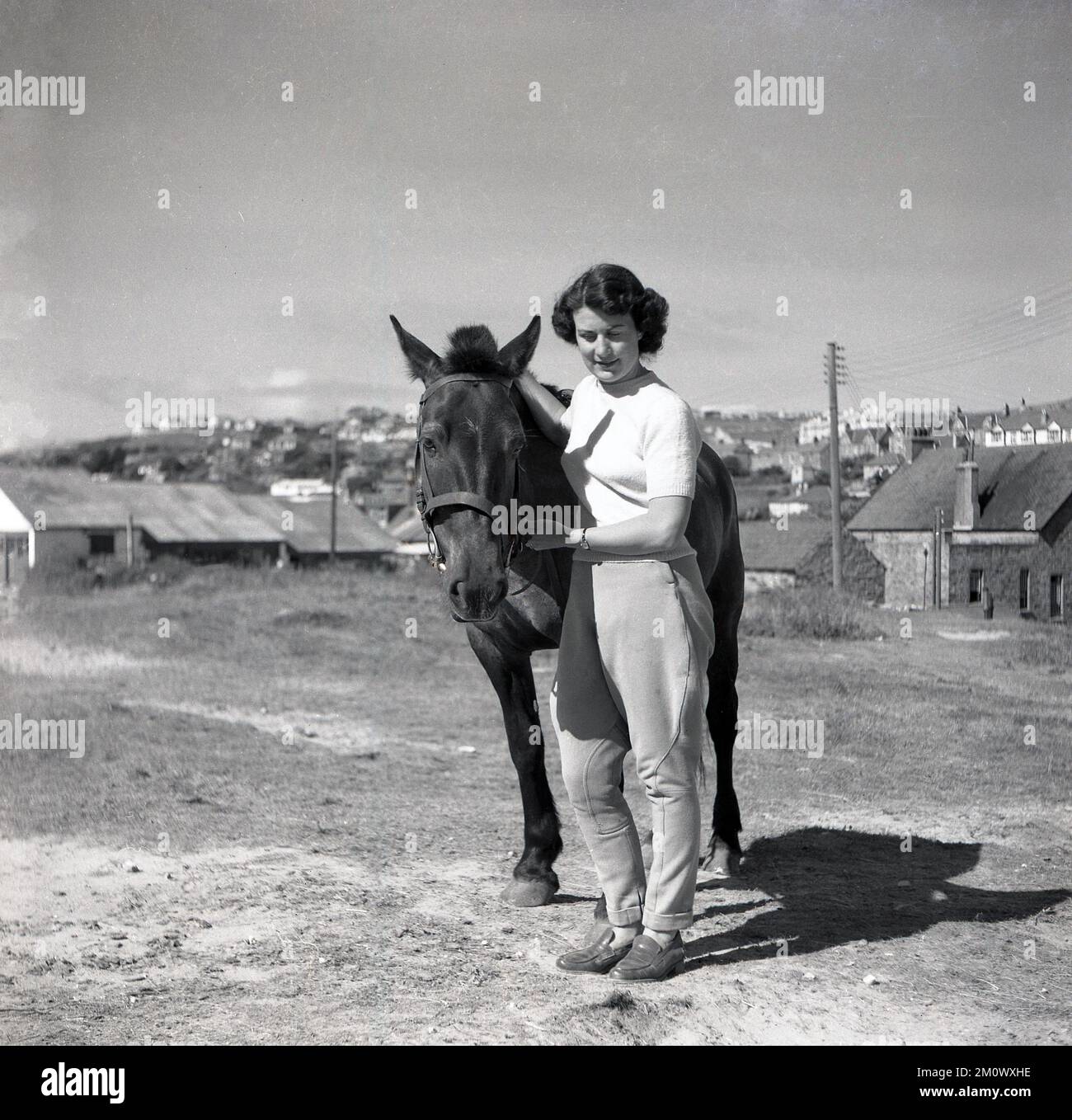 1959s, historical, a lady wearing jodhpurs standing outside with a ...