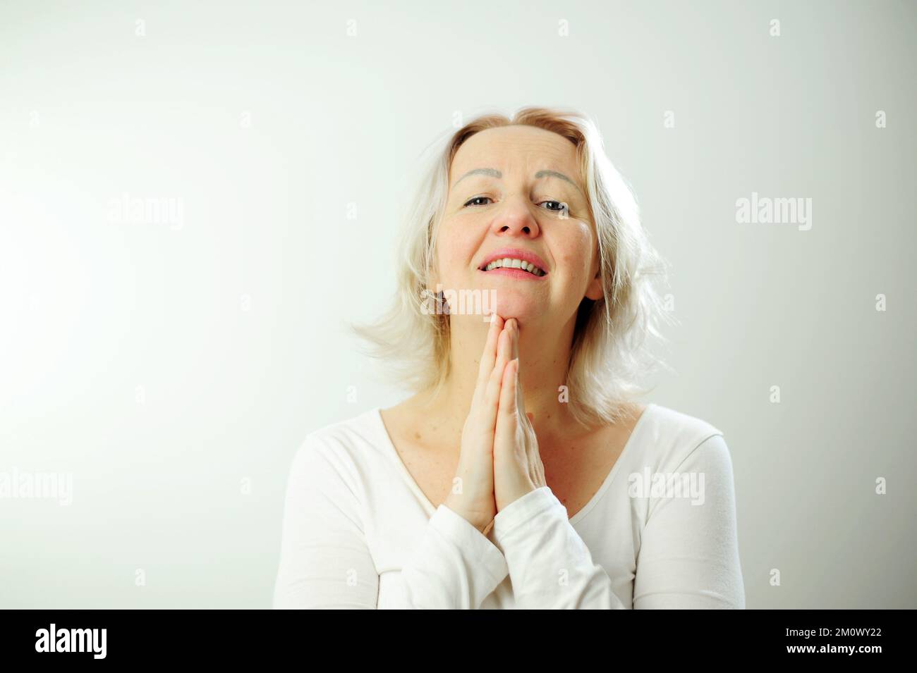 A woman prays claps her hands rejoice raises her head up looks blissful ...