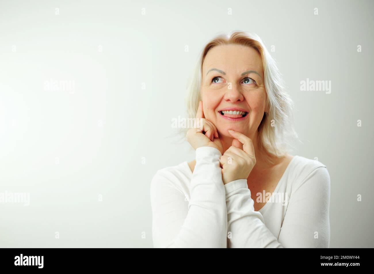 Happy mature blonde lady sitting on couch, holding video call with friends, head shot close up ...