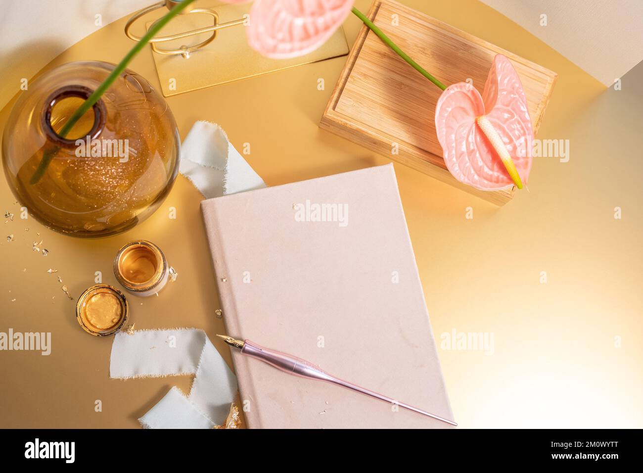 Composition of pink diary with fountain pen, writing ink and vase with ...