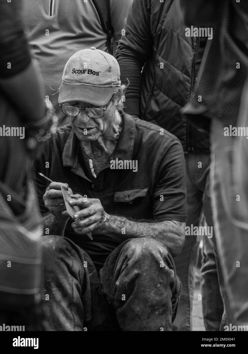 A selective focus of a man sitting and writing on a sheet of paper ...