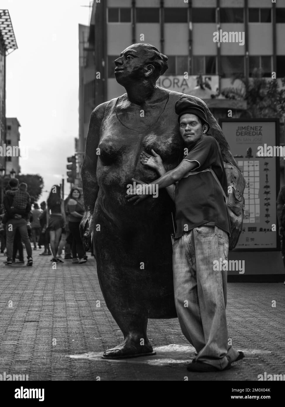 A vertical grayscale of a male leaning on a statue in the street Stock ...
