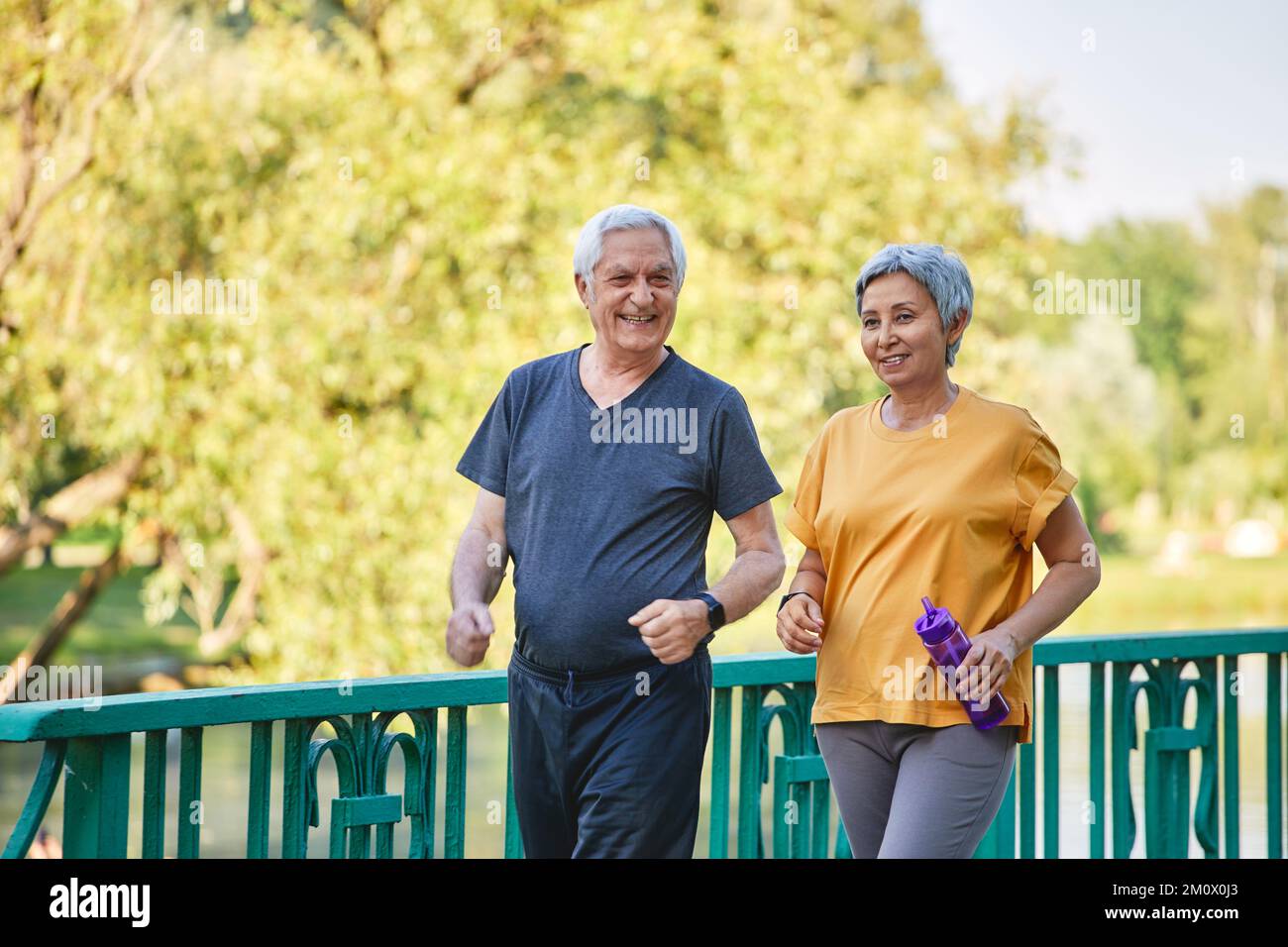 Older Asian and Caucasian wife and husband wear activewear strolling ...