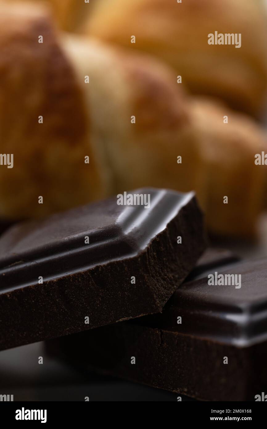 A vertical closeup of a dark chocolate bars on a blurry pastry ...