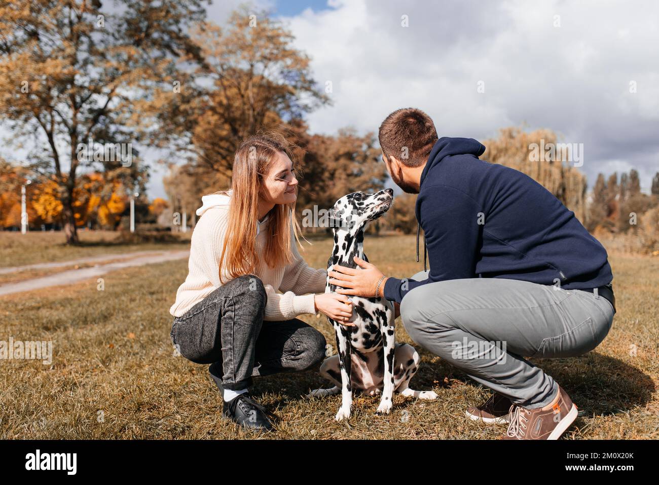 A young couple is having fun with a Dalmatian dog outdoors Stock Photo ...