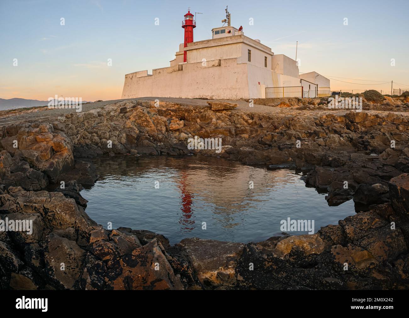 The historic Cabo Raso lighthouse reflecting in the small pond in front ...