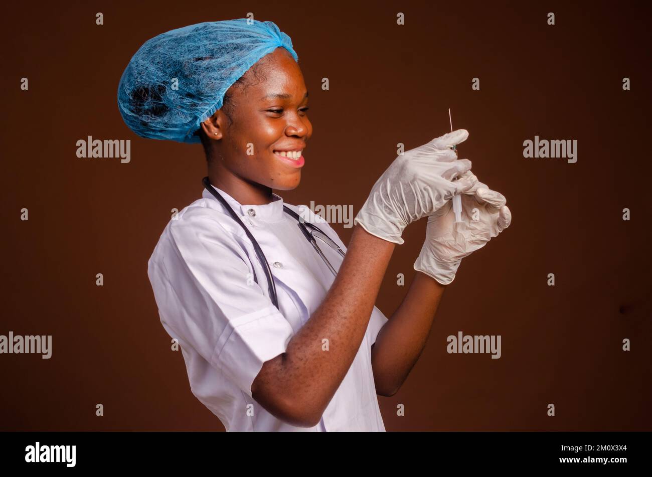 A happy young black nurse holding an injection needle isolated on brown ...