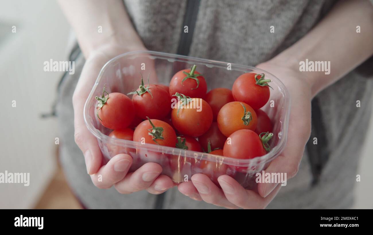 Woman shows ripe red cherry tomatoes grown on a plantation for sale ...