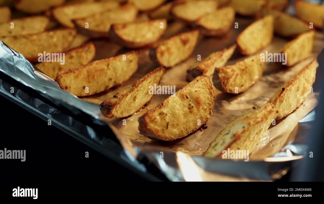 Baked potato wedges with rustic spices on a baking sheet with foil ...