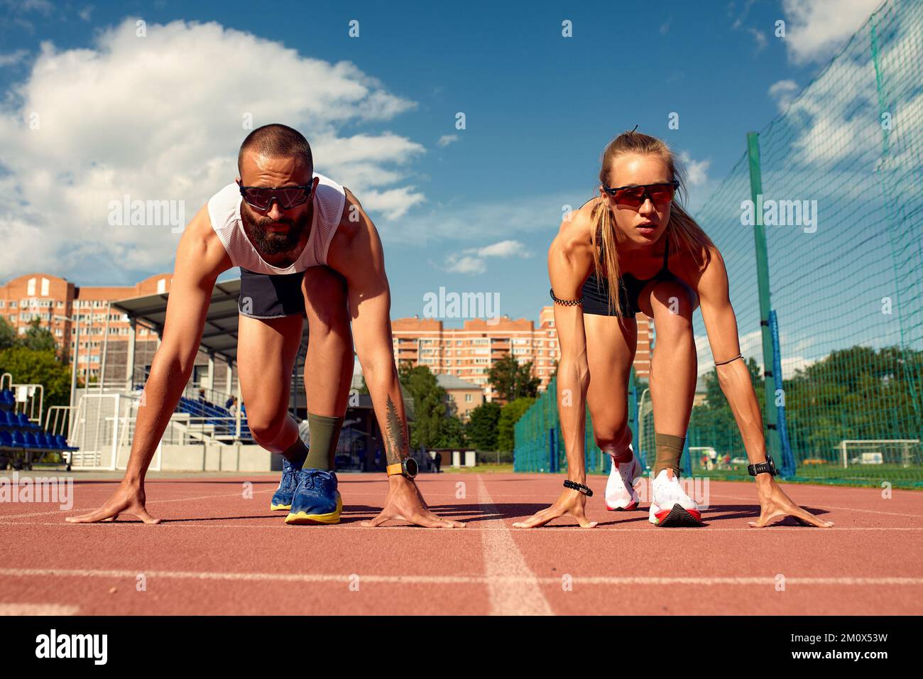 Young sporty woman and man are ready to run on racetrack. Fit well ...