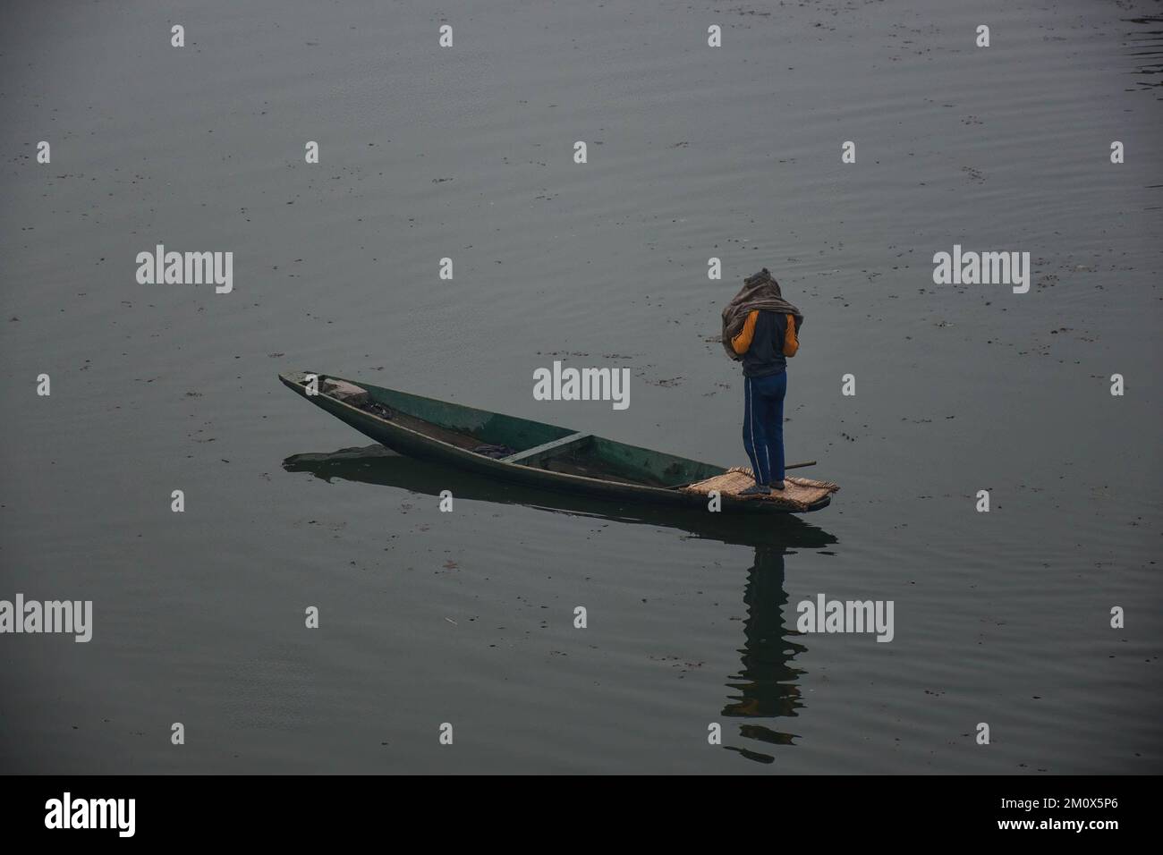 A man seen wearing a Pheran (traditional attire) as he rows his boat ...