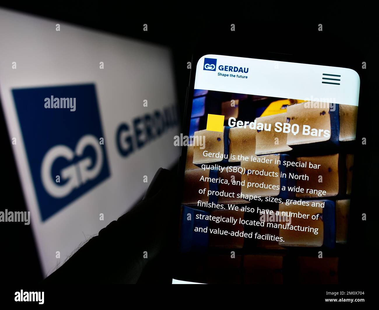 Person holding cellphone with webpage of Brazilian steel company Gerdau ...