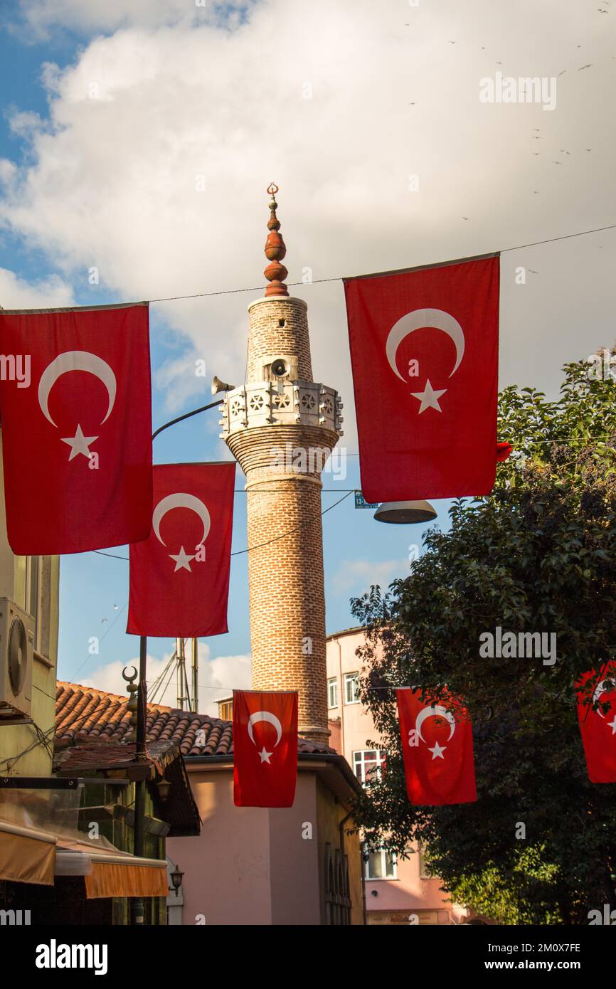 Turkish national flag hang on a pole on a rope with a minaret behind ...