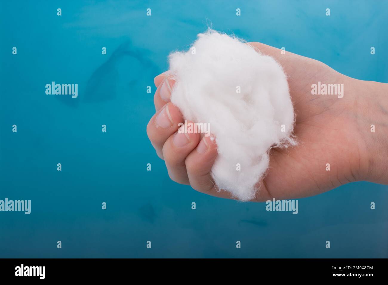 Hand holding some cotton in hand over blue water Stock Photo - Alamy