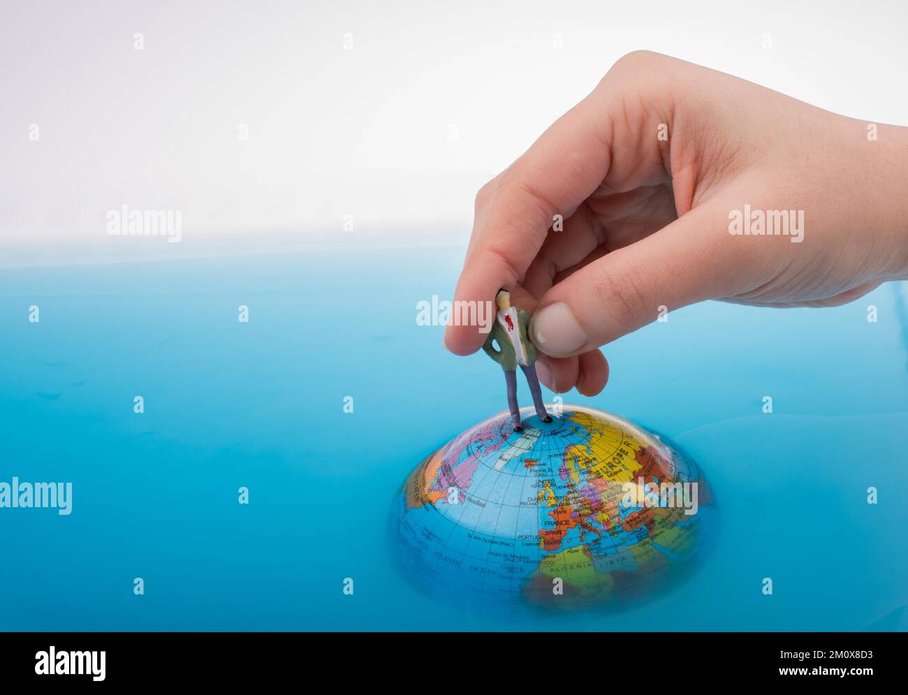 Hand holding a little figurine on the top of the globe in water Stock ...
