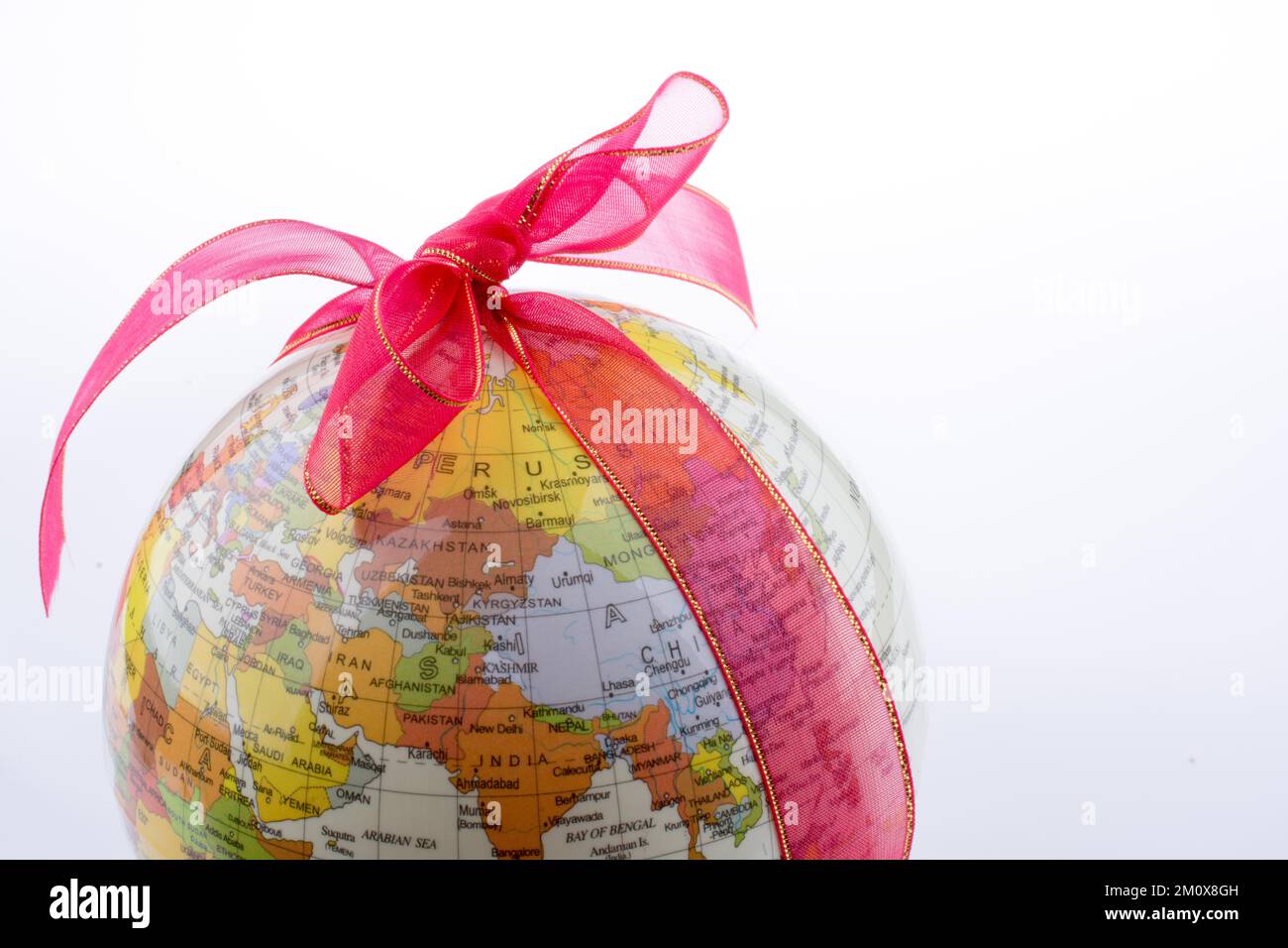 Globe tied with red ribbon on a white background Stock Photo - Alamy