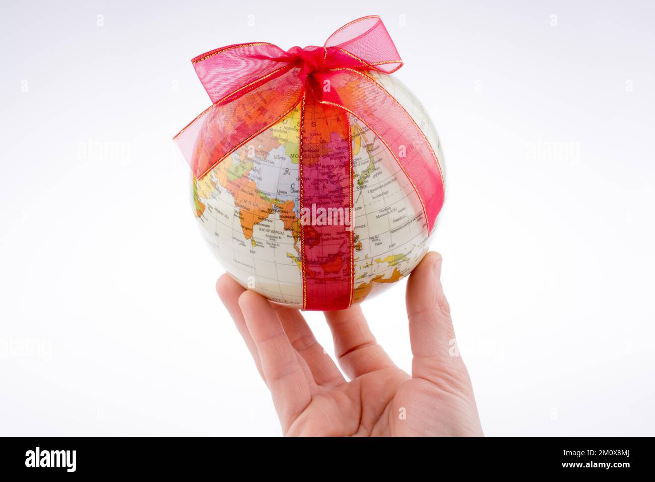 Globe tied with red ribbon on a white background Stock Photo - Alamy