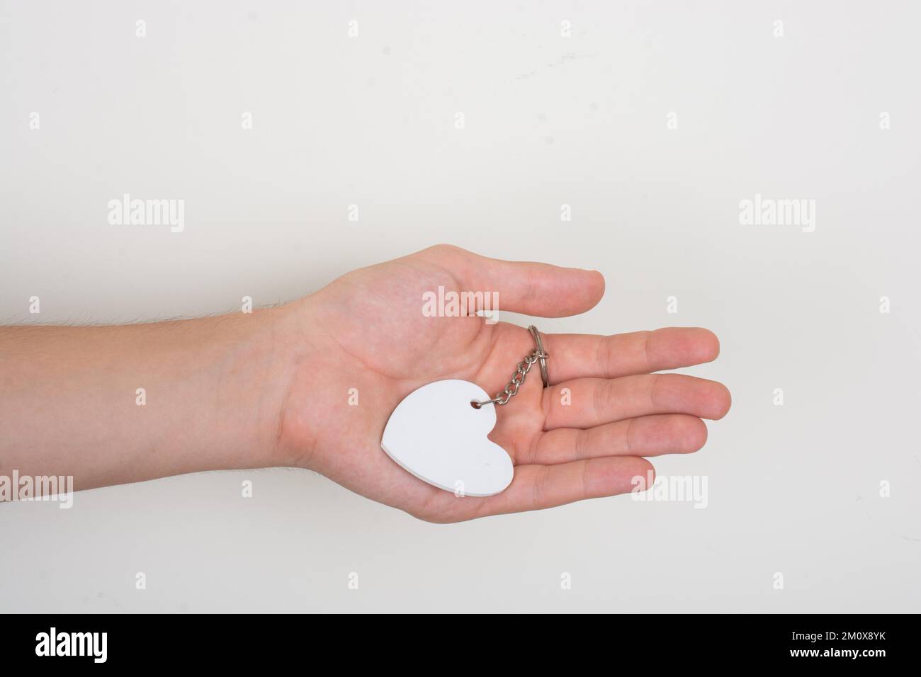 Heart shaped white object in hand on white background Stock Photo - Alamy