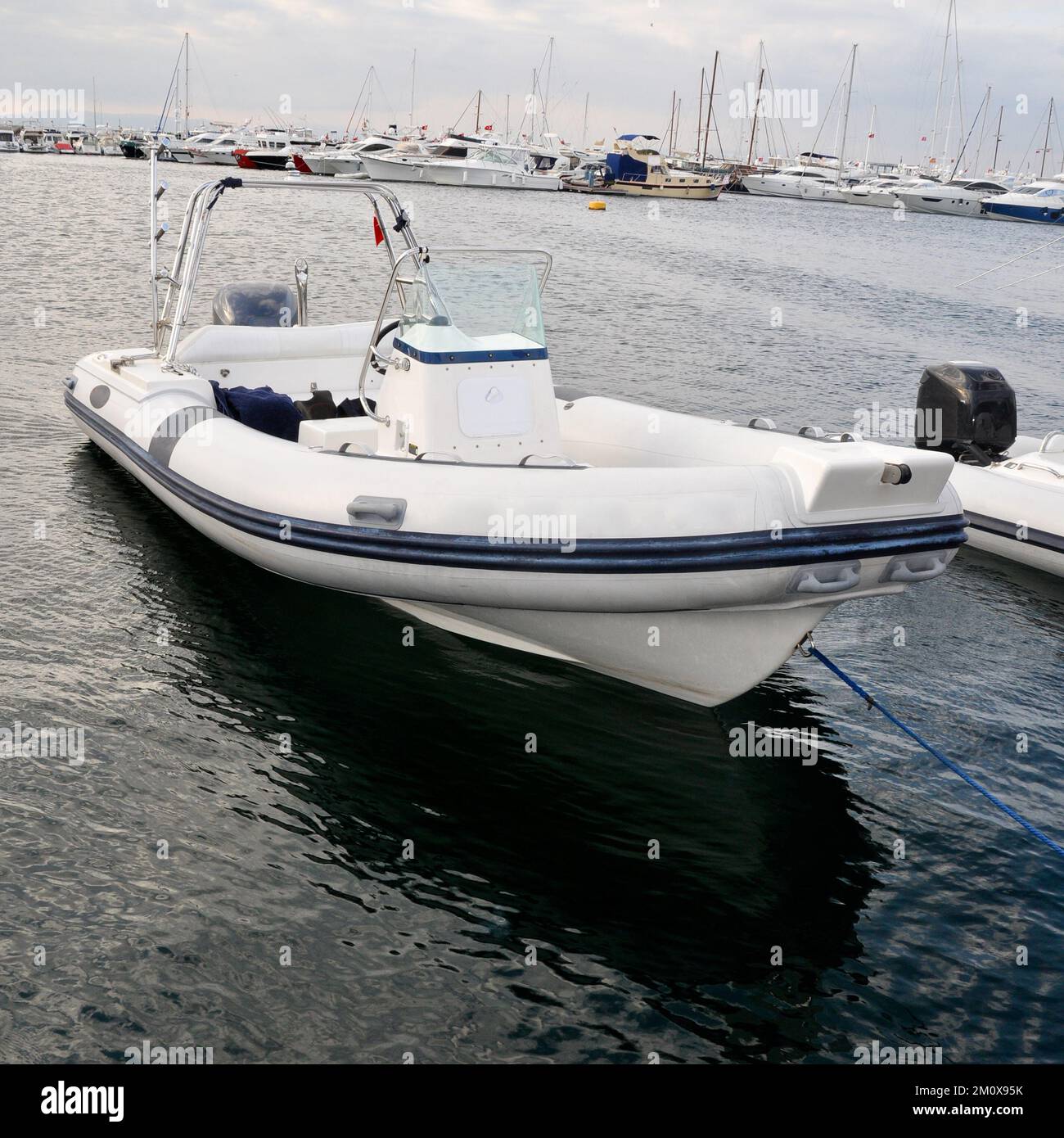 Modern inflatable boat with engine in the sea near shore, blue white ...