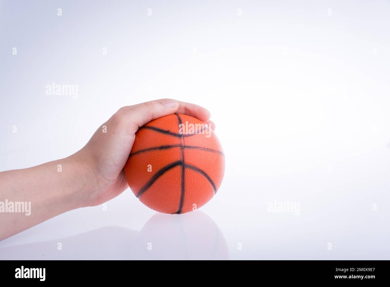 Hand holding an orange basketball model on a white background Stock ...