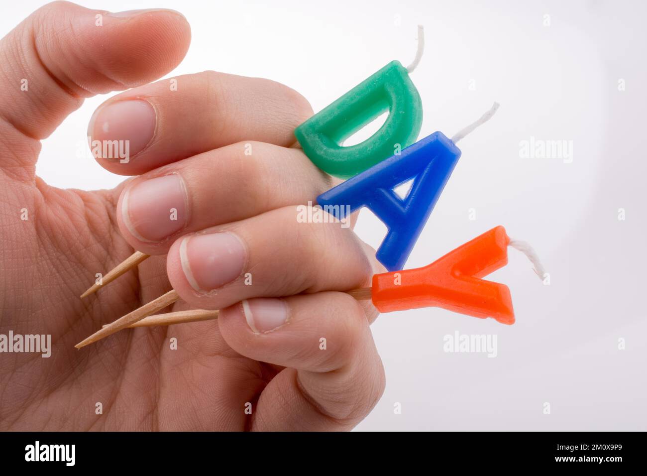 Color candles on sticks in hand write the word day Stock Photo - Alamy