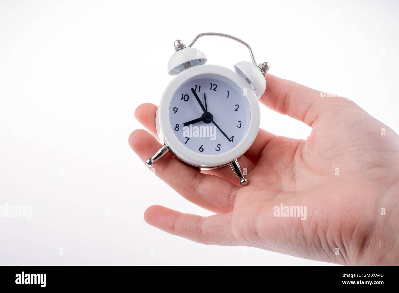 Alarm clock in hand on a white background Stock Photo - Alamy