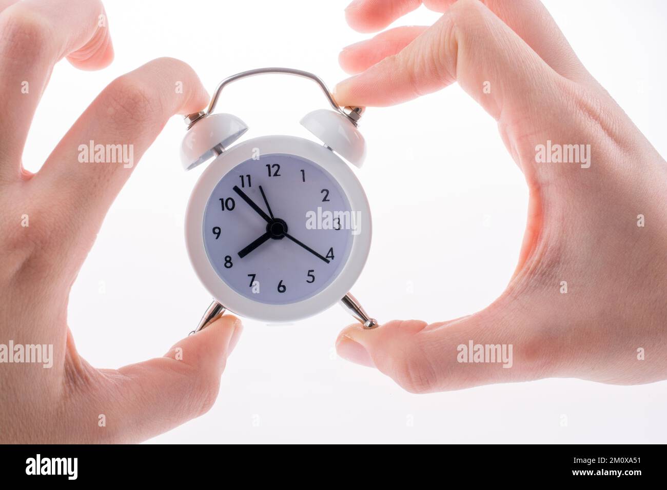 Alarm clock in hand on a white background Stock Photo - Alamy