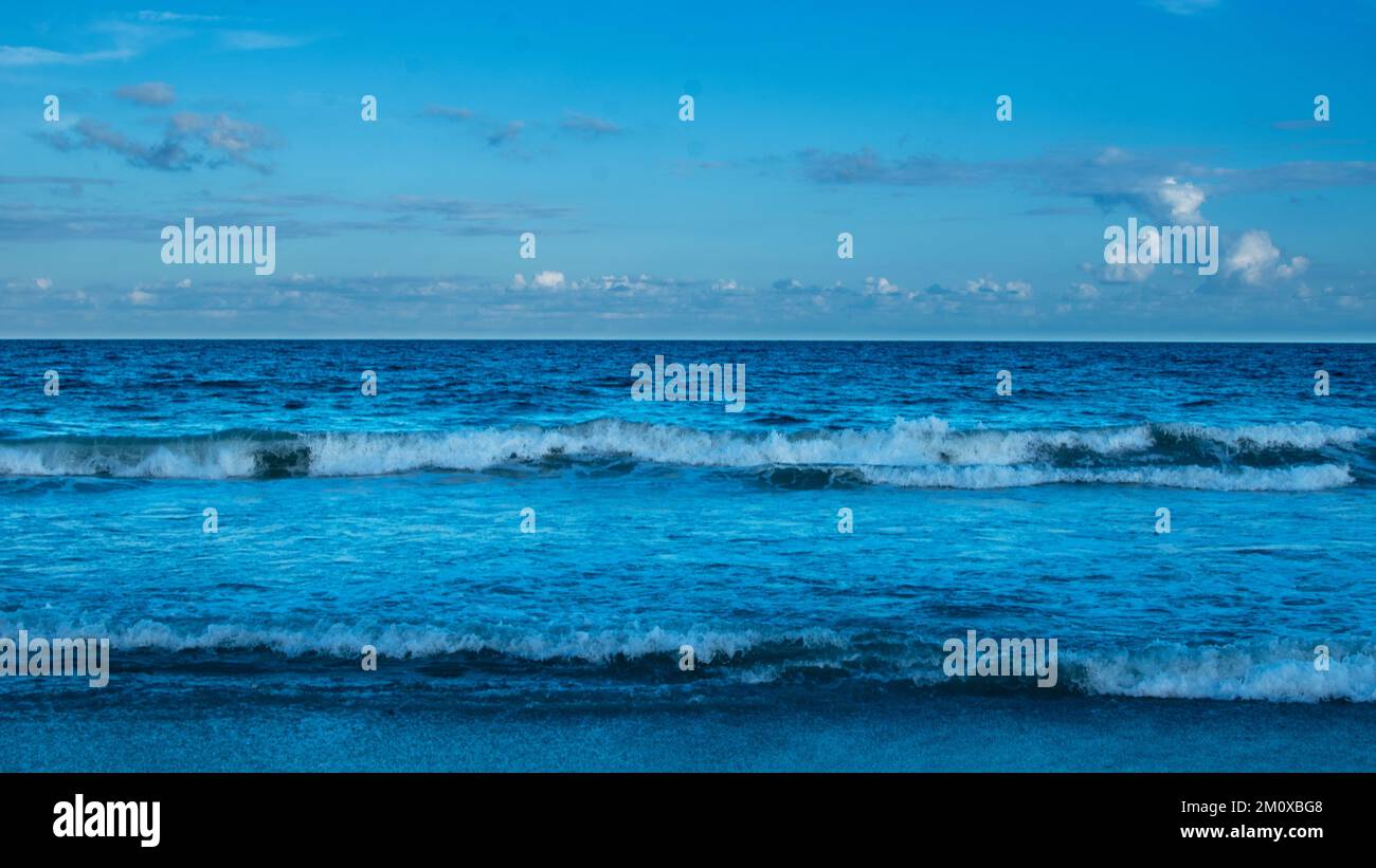 A scenic view of sea waves hitting the coast at sunset Stock Photo - Alamy
