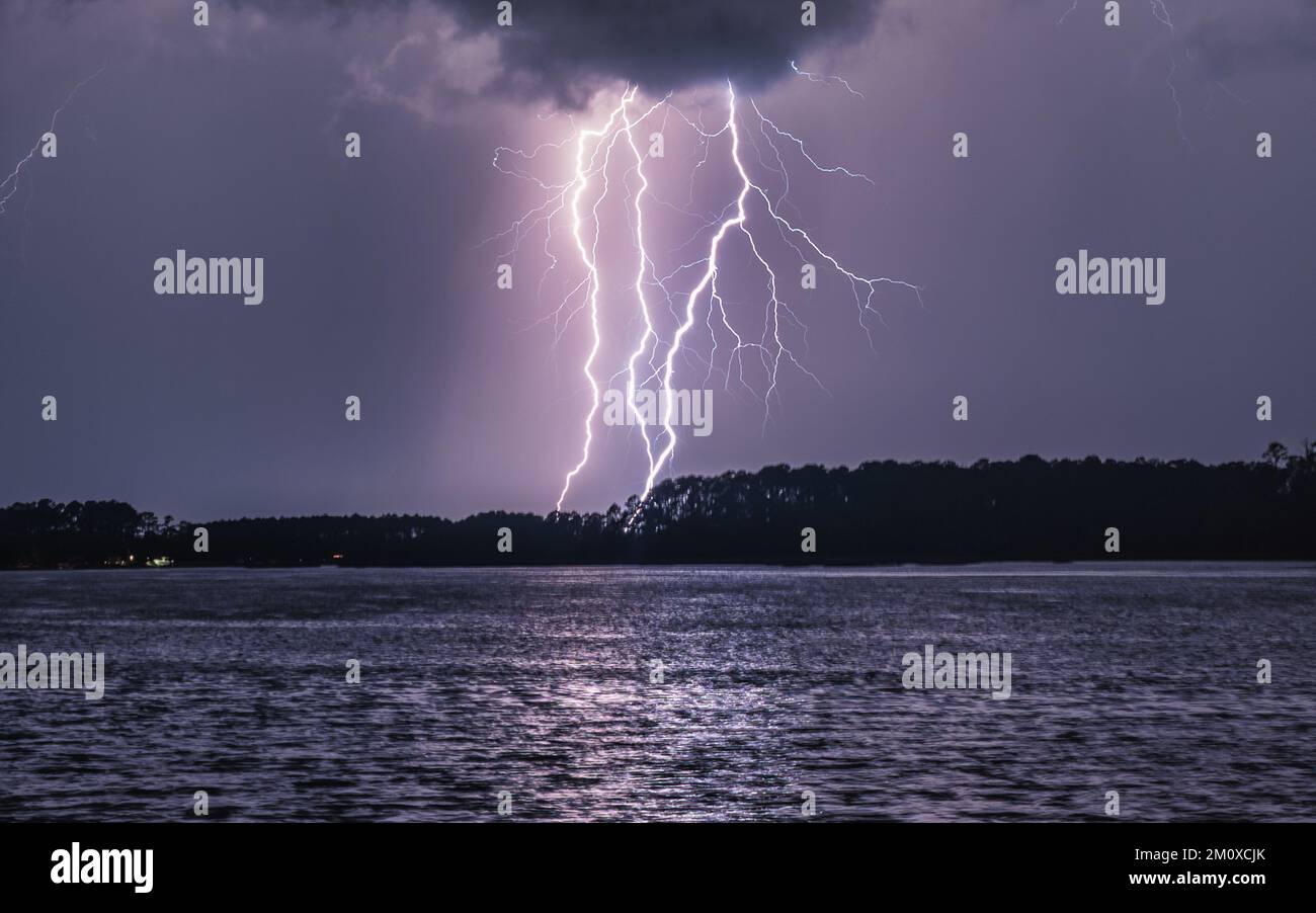 A beautiful shot of triple close lightning strikes with reflection on ...