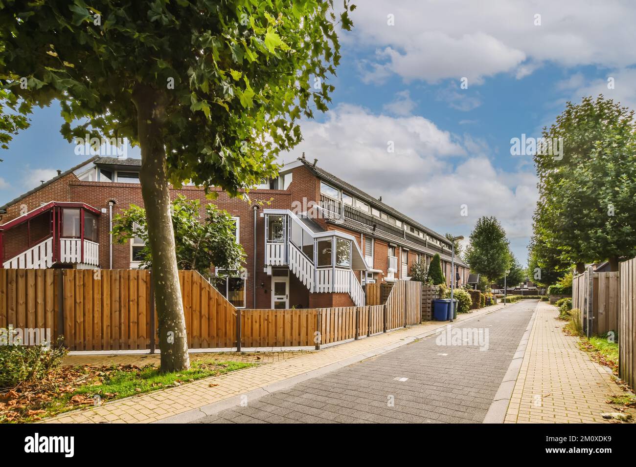 a street with houses in the background and trees on both sides, some ...