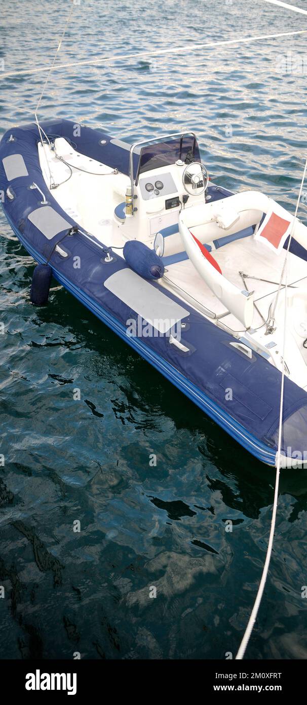 Modern inflatable boat with engine in the sea near shore, blue white ...