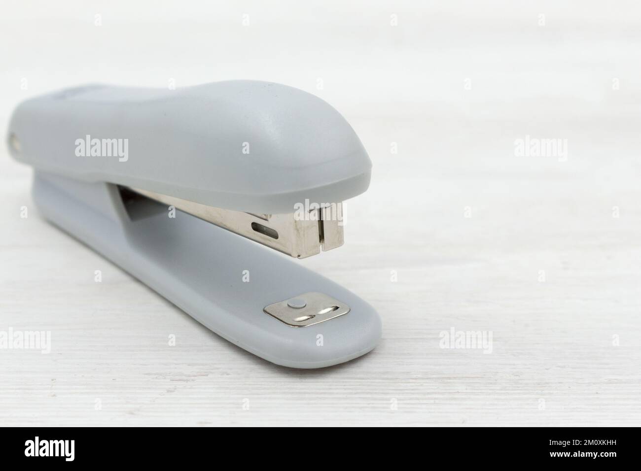 A gray stapler is lying on a white wooden table. office stationery ...