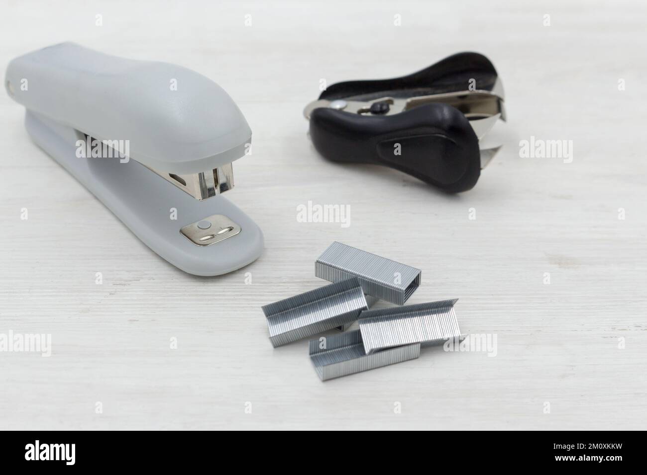 Gray stapler, anti-stapler with clerical staples on a white wooden ...