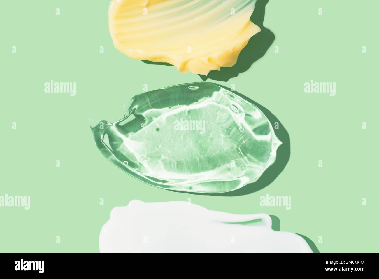 Cream and gel smears over green background, various cosmetic products ...