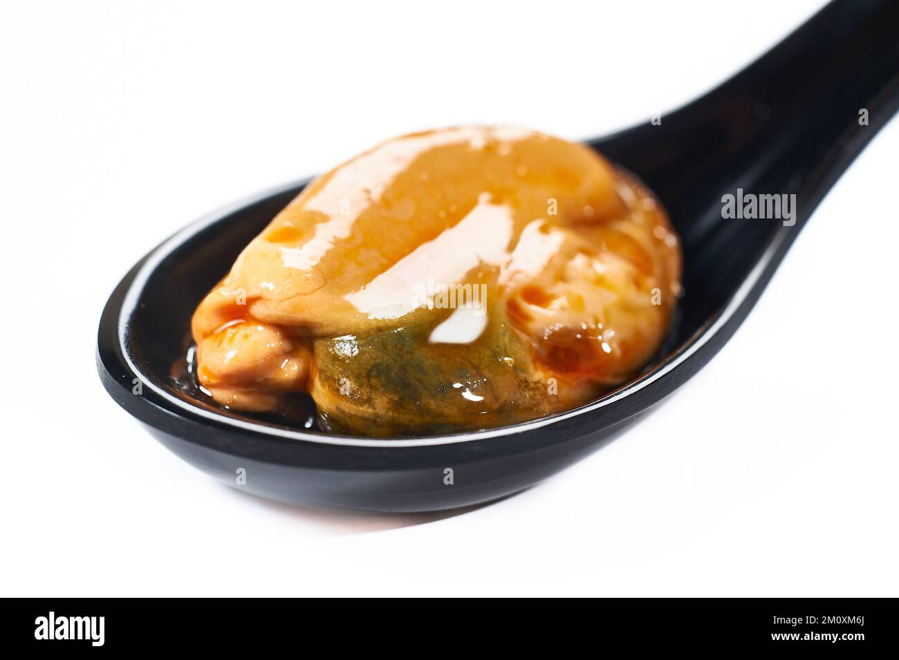 Close-Up of big mussel without shell on a black spoon on a white ...