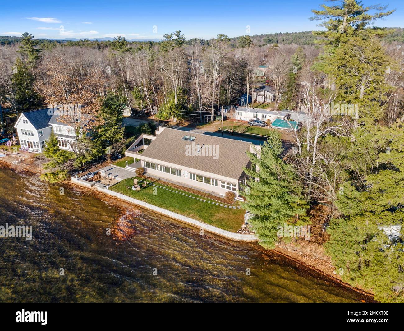 An aerial shot of the lakefront home with deciduous trees in the ...