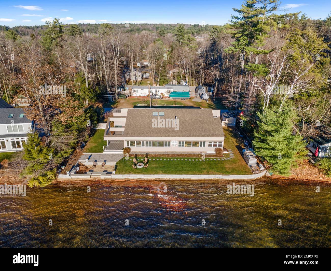 An aerial shot of the lakefront home with deciduous trees in the ...