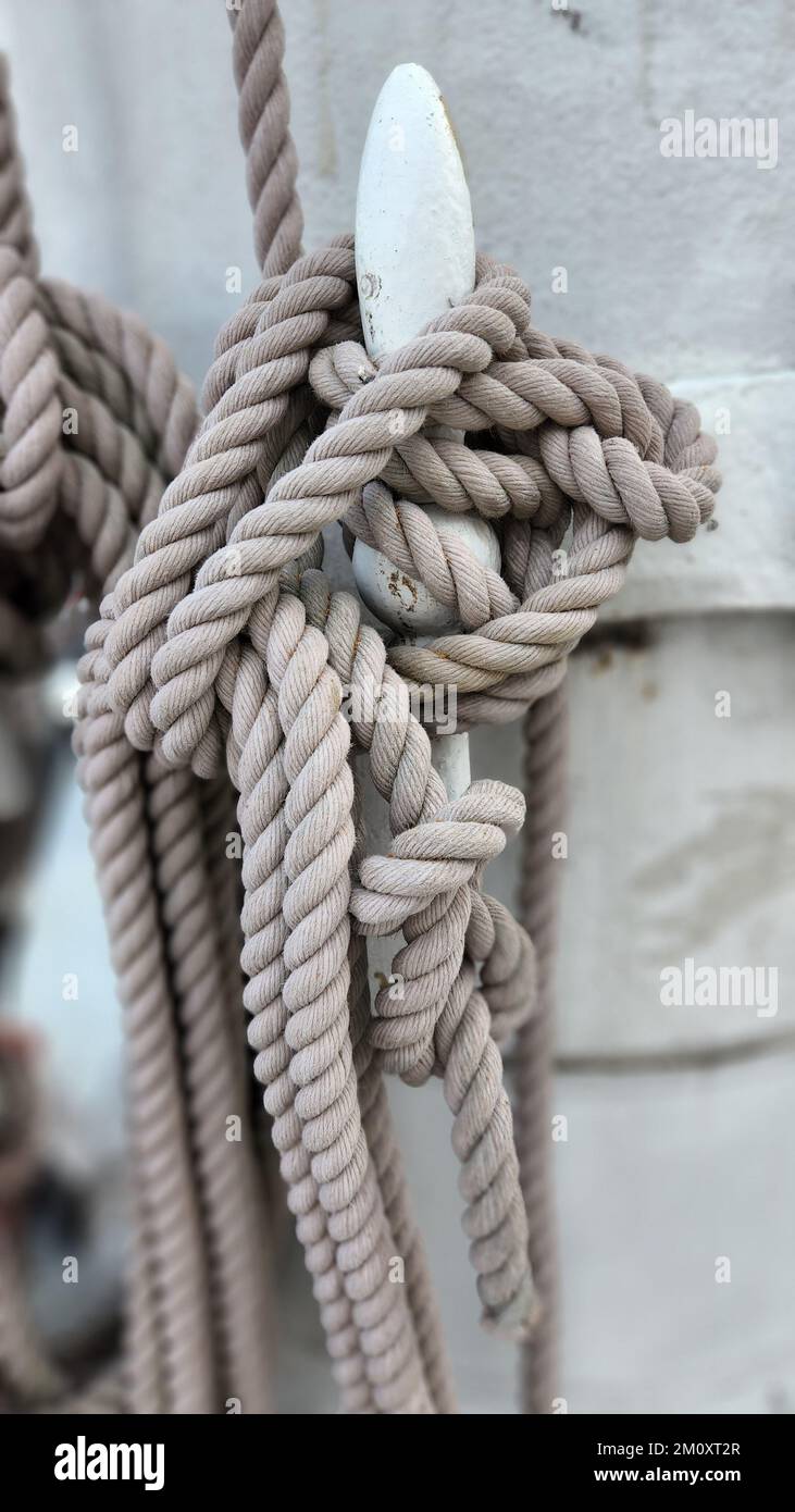 A vertical close-up shot of details of sail rope on the mast of a ...