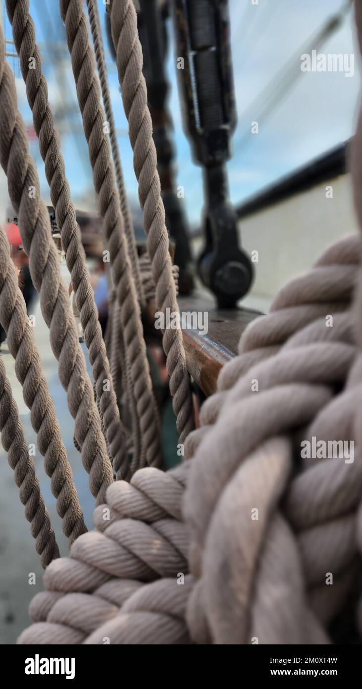 A vertical closeup of ropes and rigging on an old sail ship holding up ...