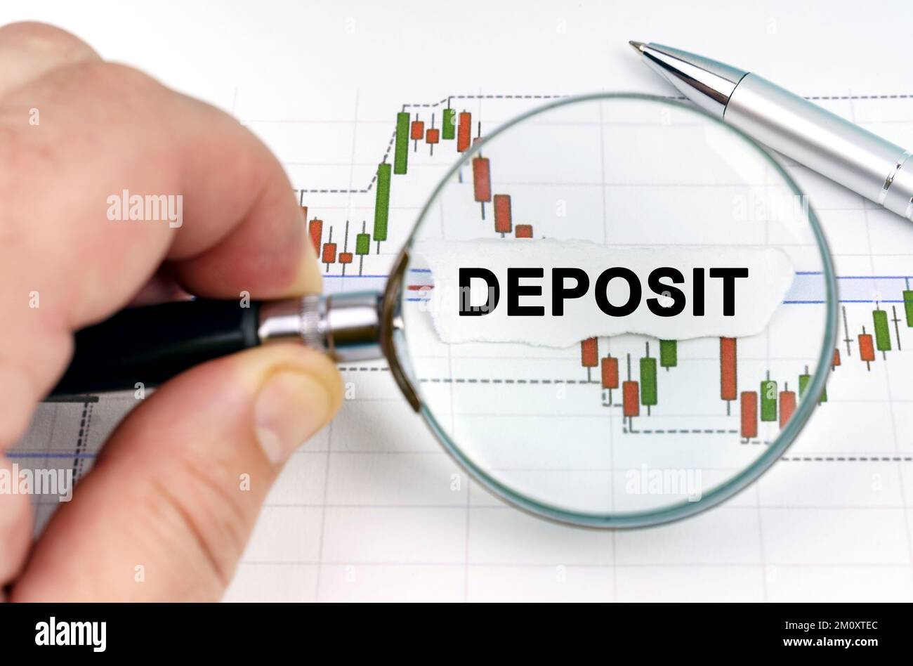 Economy concept. A man looks through a magnifying glass at charts and ...
