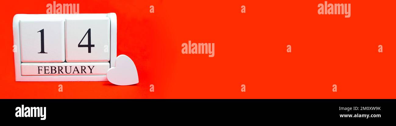 February 14 number on a white calendar and a wooden heart on a red ...