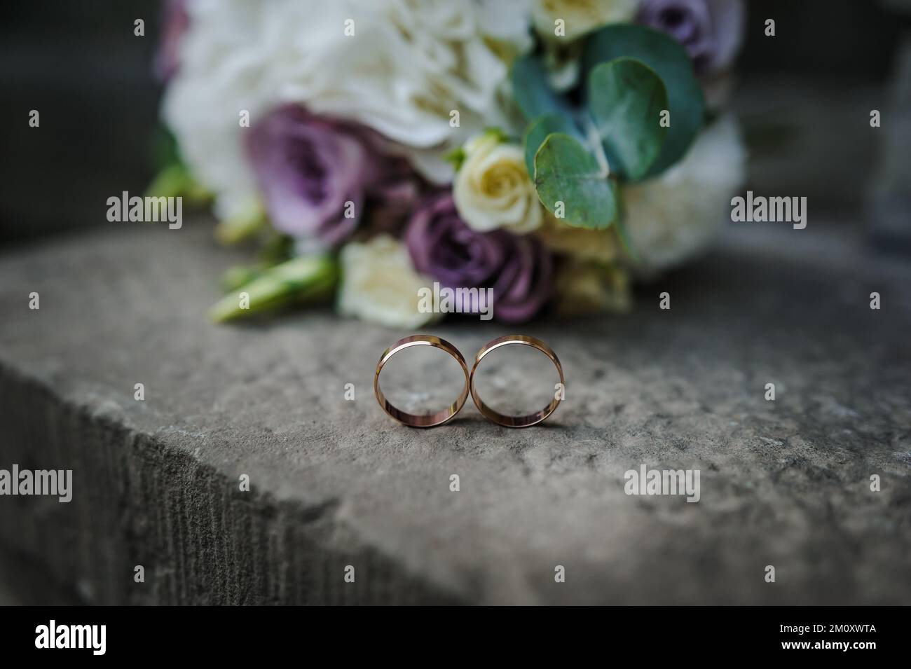 Golden wedding rings, in the background the bride's bouquet of multi ...