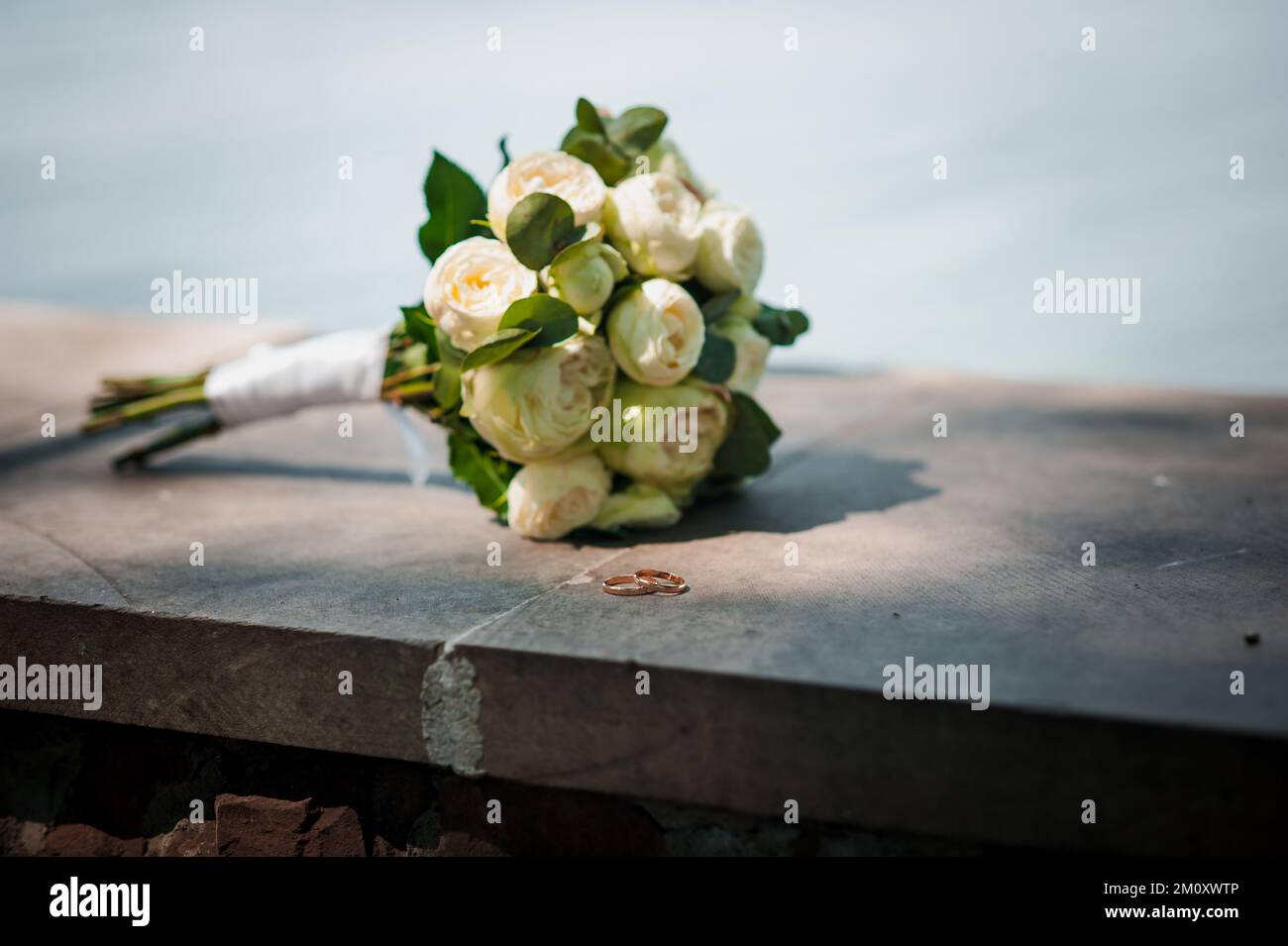 Golden wedding rings, in the background the bride's bouquet of multi ...