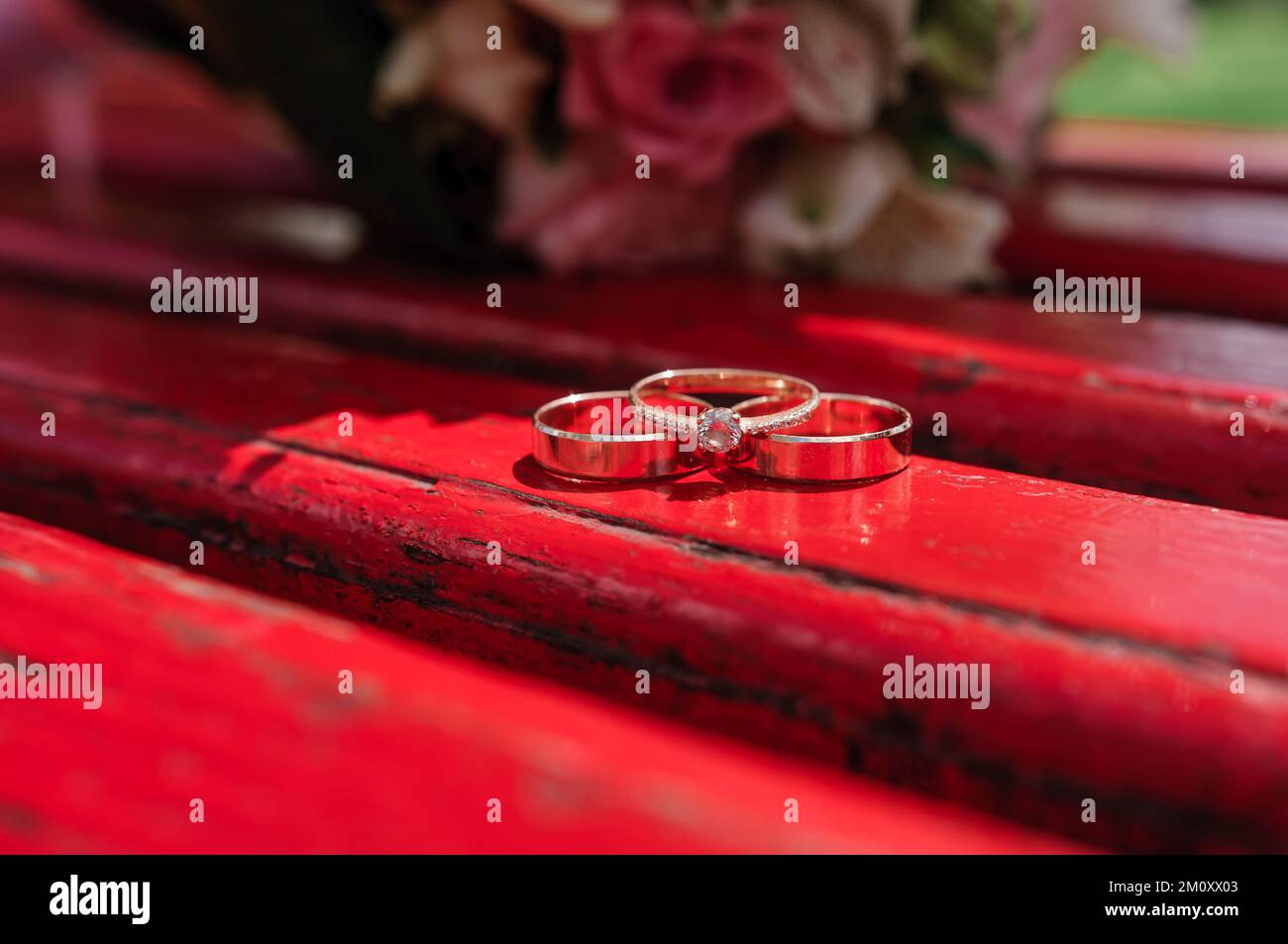 Golden wedding rings, in the background the bride's bouquet of multi ...