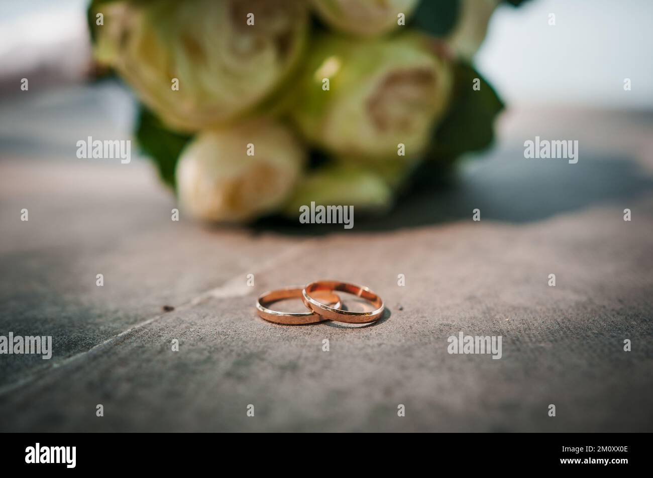 Golden wedding rings, in the background the bride's bouquet of multi ...