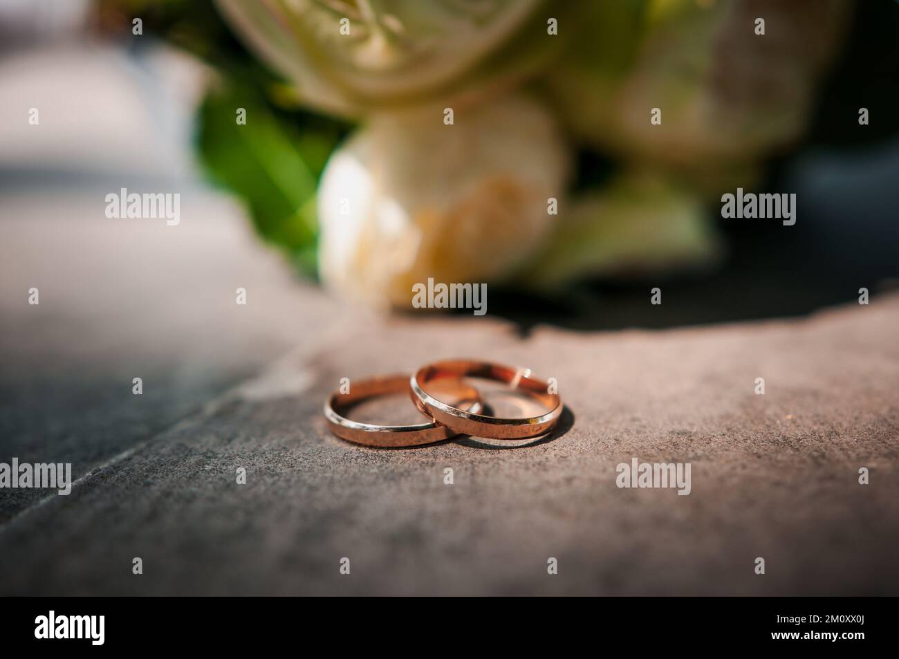 Golden wedding rings, in the background the bride's bouquet of multi ...