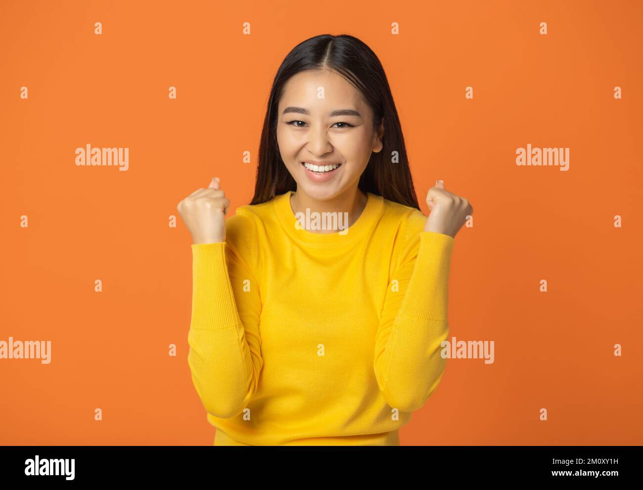 excited young woman in a yellow sweater clenches fists have good mood ...