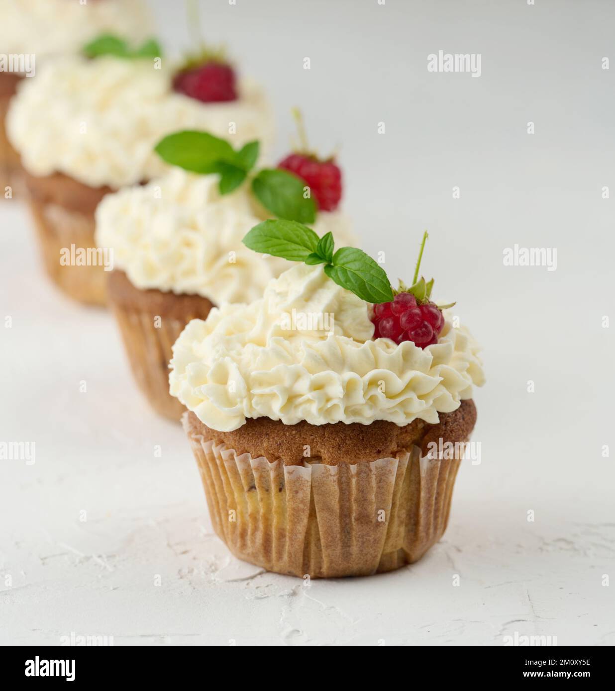 Baked cupcakes with white butter cream on the table, delicious dessert ...